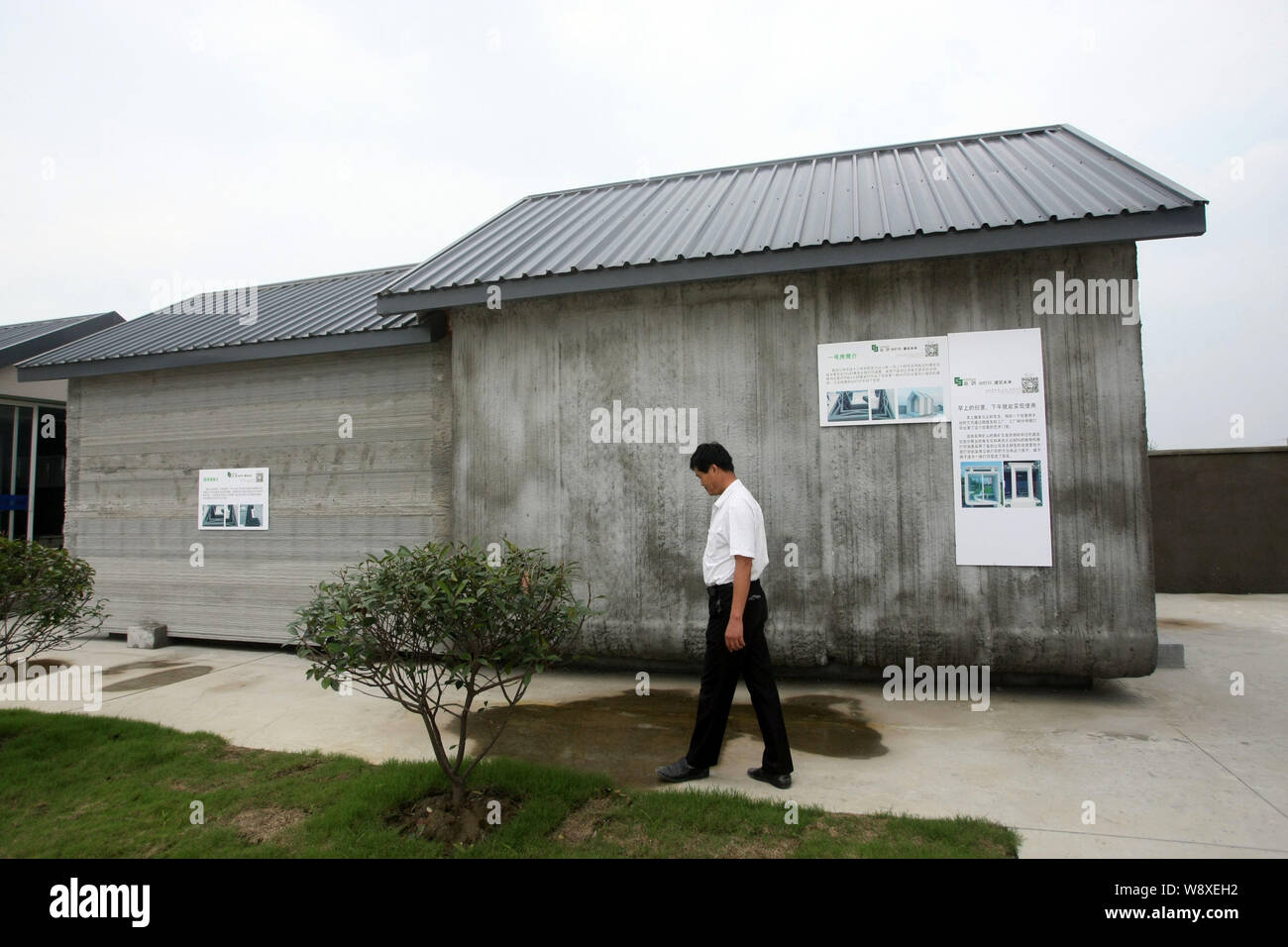 A man walks past one of the ten 3D printed houses at the Qingpu Park of ...