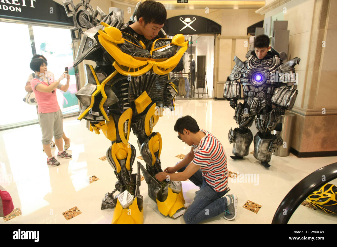 A staff member helps a performer put on his Transformers costume during ...