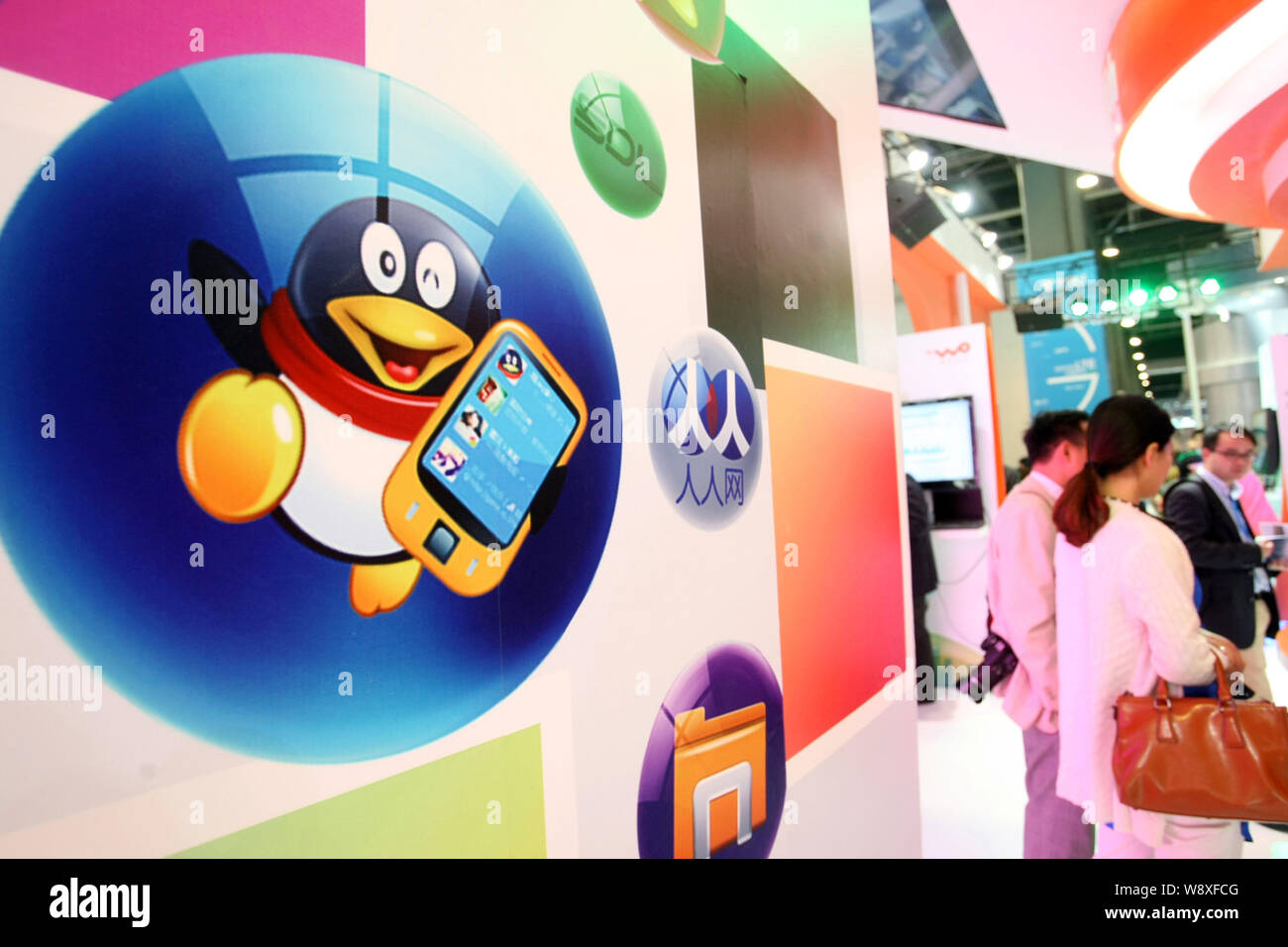 --FILE--Visitors walk past an advertisement for Mobile QQ of Tencent ...