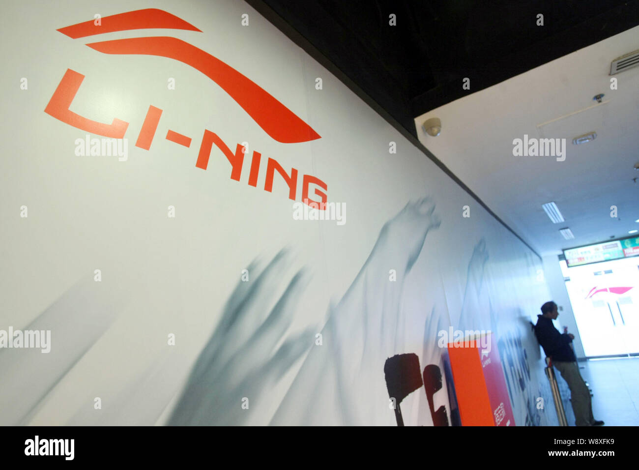 --FILE--A pedestrian stands in front of an advertisement for Li-Ning ...