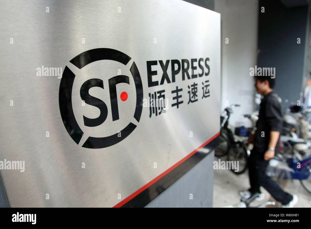 --FILE--A Chinese employee walks towards a branch of SF Express in ...