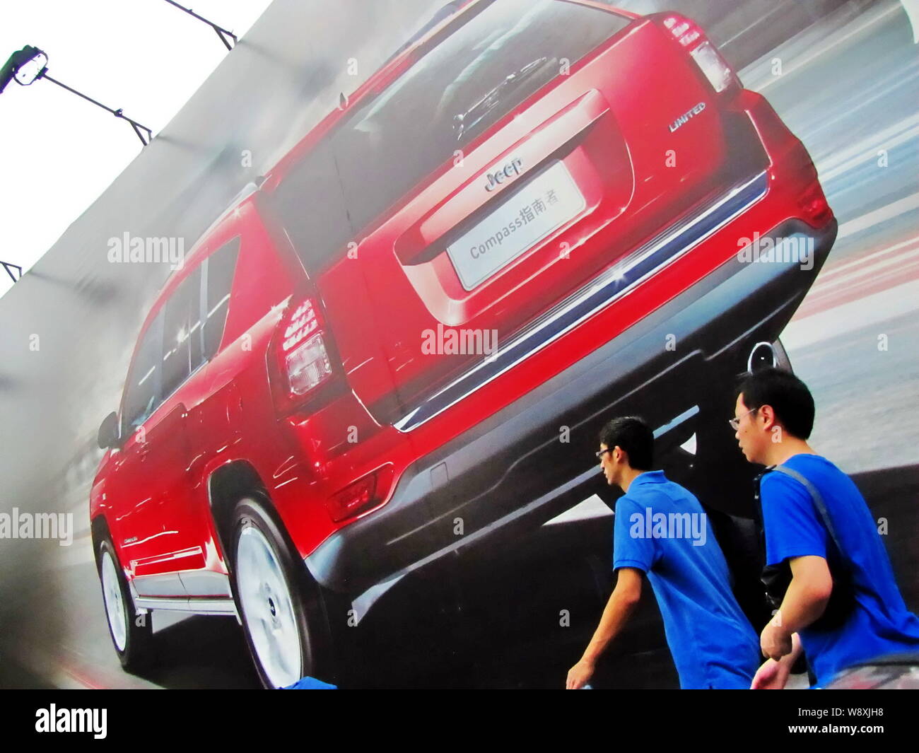 --FILE--Pedestrians walk past an advertisement for Jeep Compass SUVs in ...