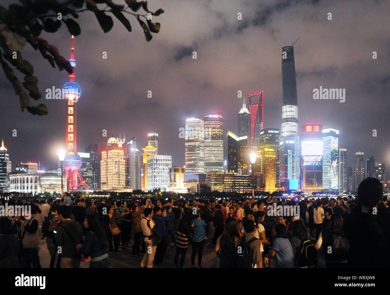 Tourists crowd the promenade on the Bund against the skyline of the ...