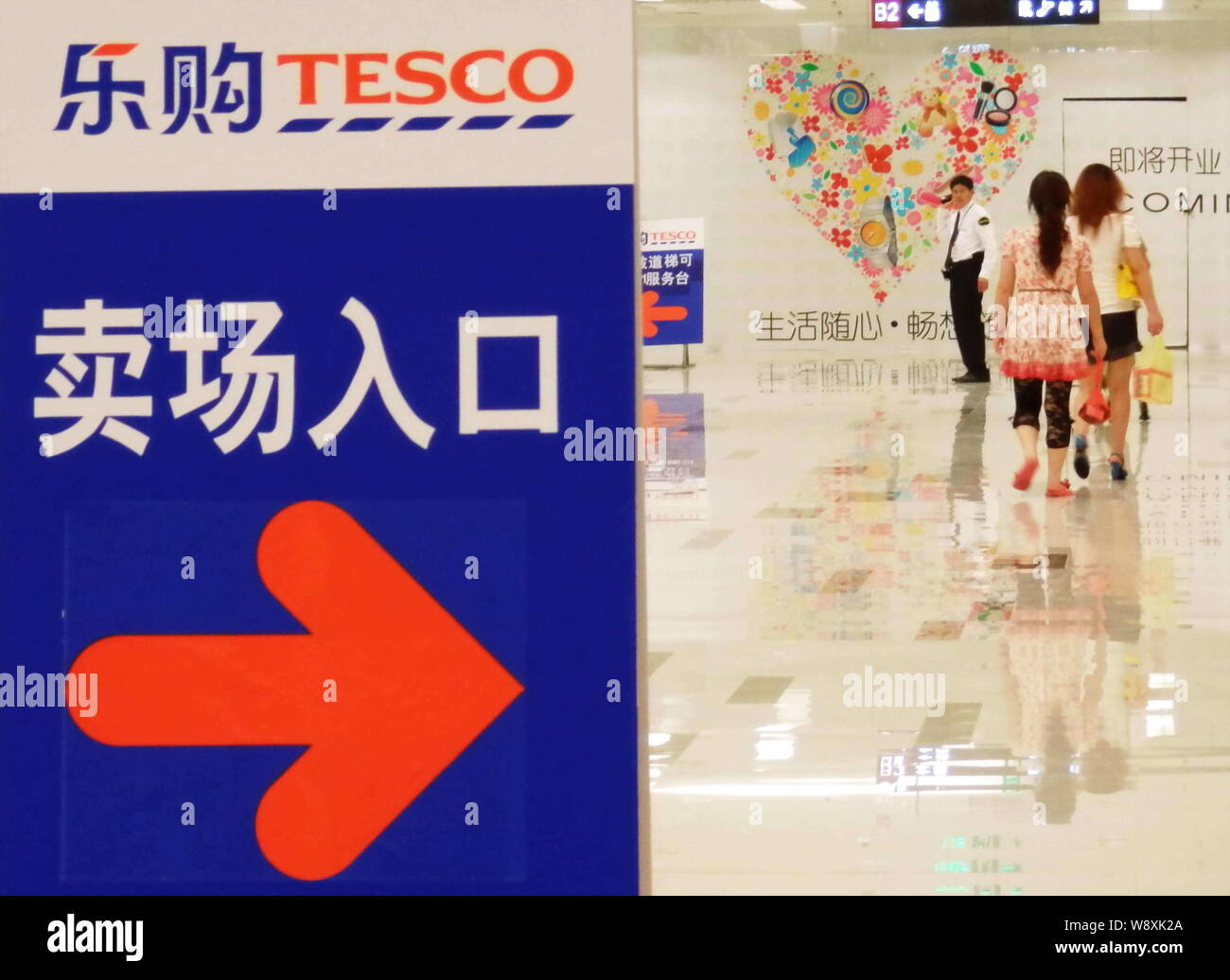 --FILE--Customers walk past an advertisement for Tesco at a Tesco ...