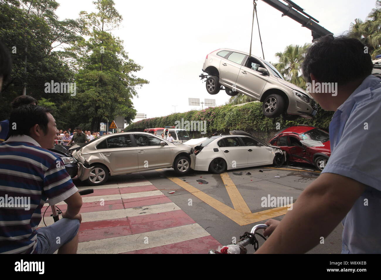A Volvo SUV is being lift by a crane from a stack of cars after a ...