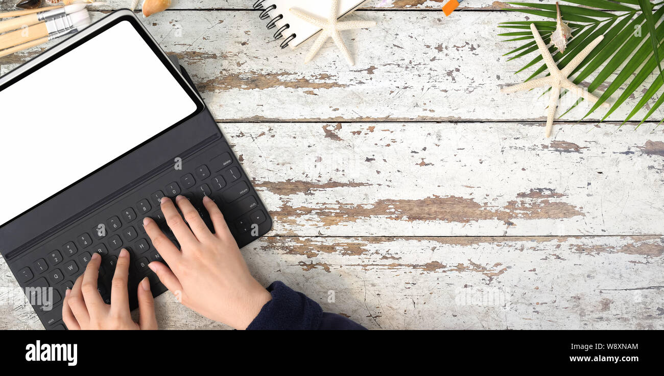 Top view of young female's hand typing in summer beach concept ...