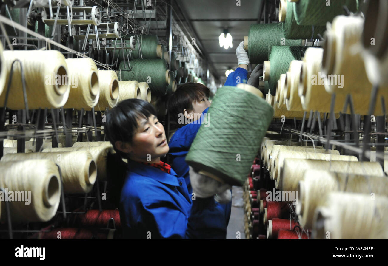 --FILE--Chinese workers stack up rolls of yarn at a carpet factory in ...