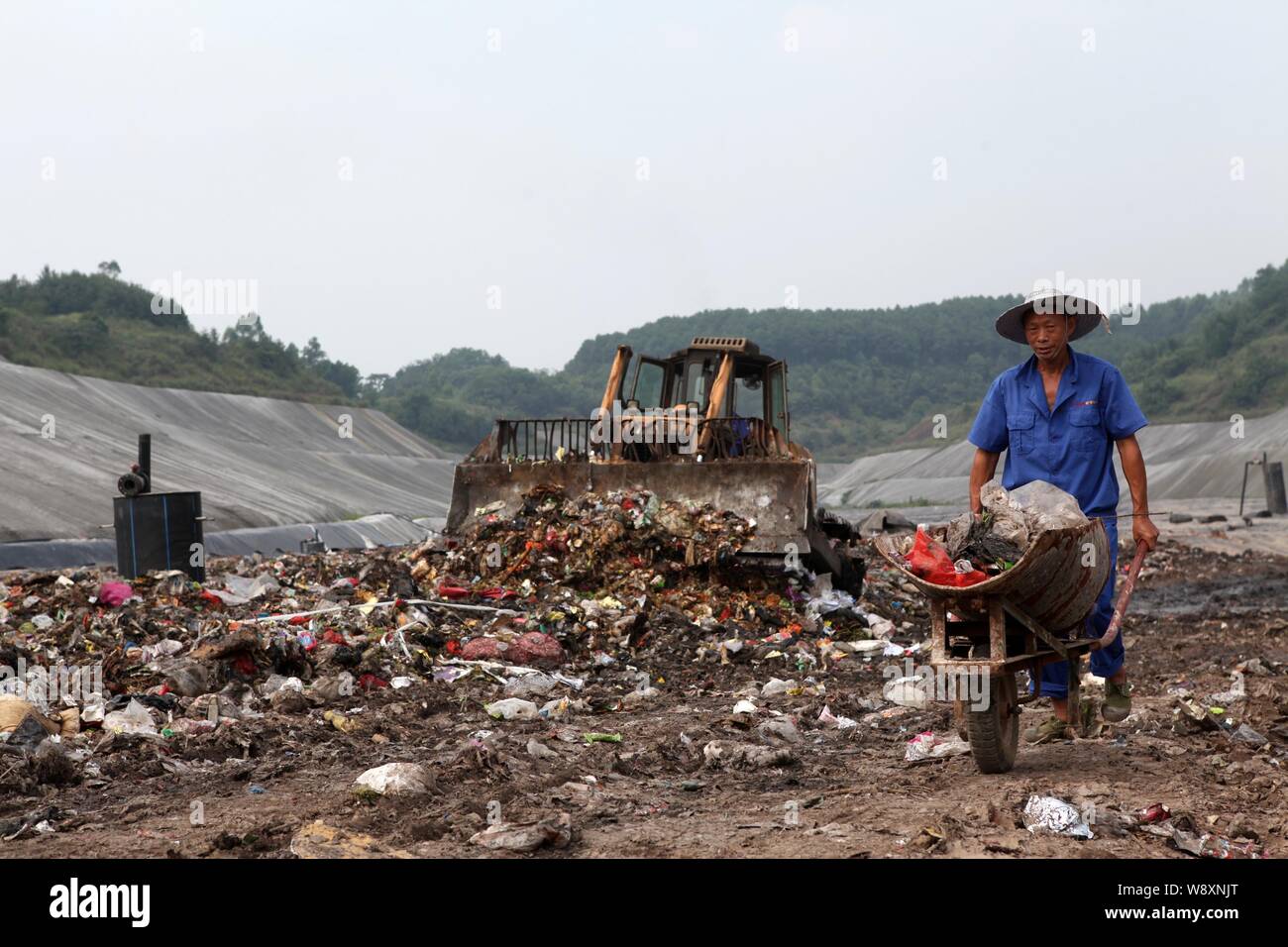 --FILE--A Chinese worker pushing a cart of garbage walks past garbage ...