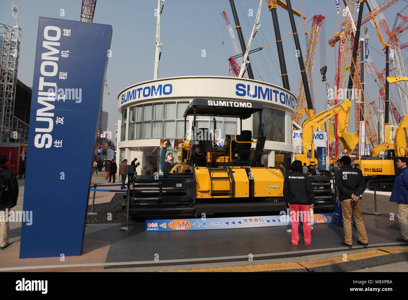 --FILE--Employees look at construction machineries of Sumitomo during ...