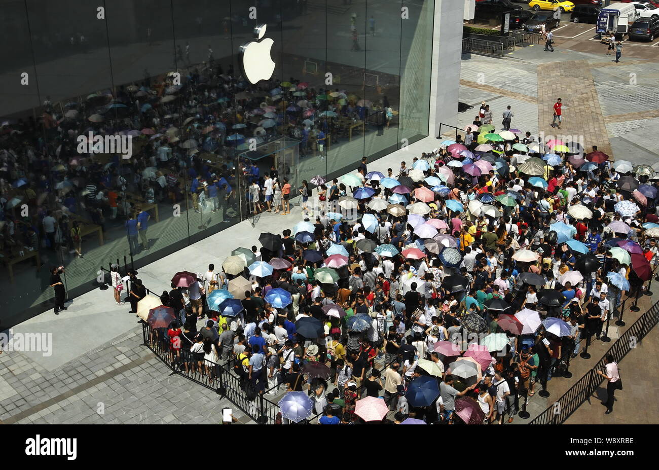Crowds of people queue up in front of the new Apple Store in Chongqing ...