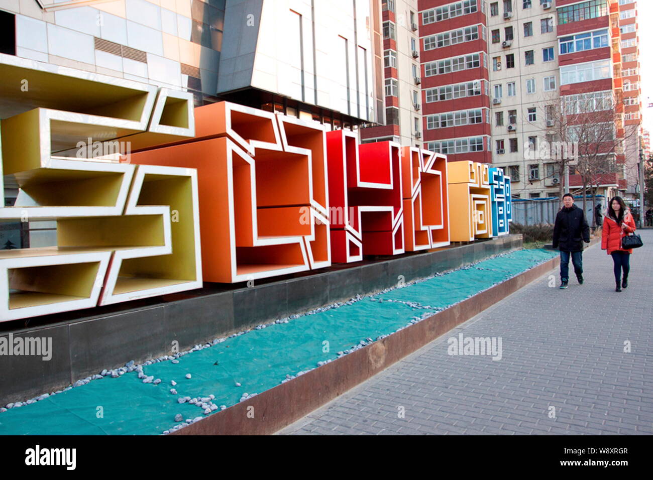 --FILE--Pedestrians walk past a signboard of Shangdu SOHO developed by ...