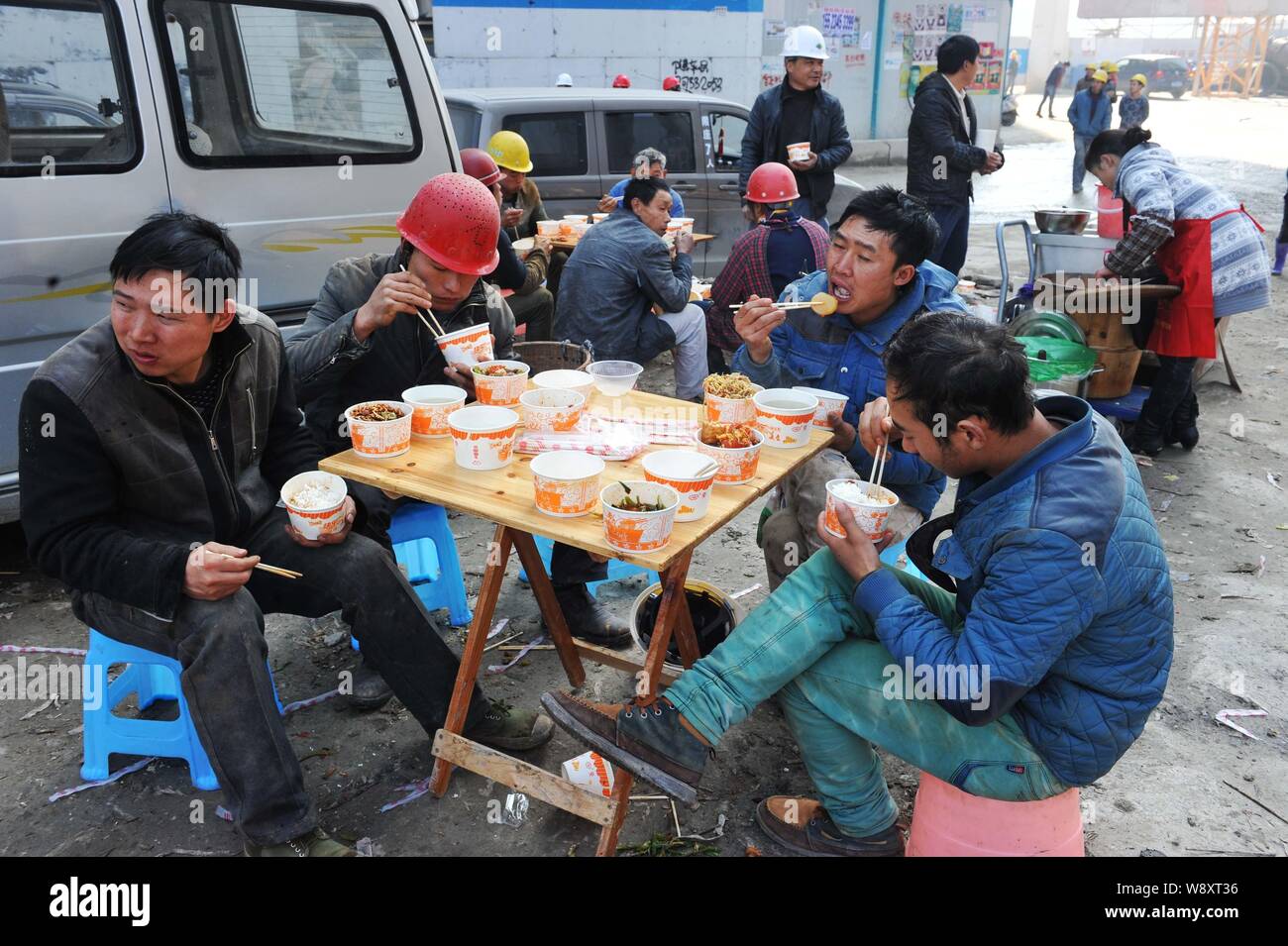 Chinese migrant workers eat lunch at the construction site of a ...
