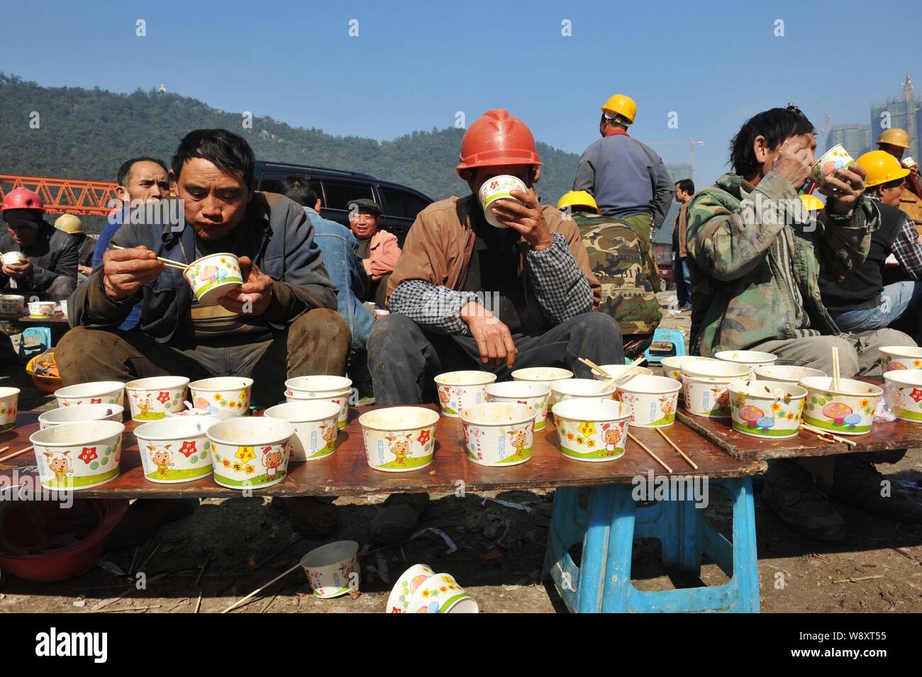 Chinese migrant workers eat lunch at the construction site of a ...
