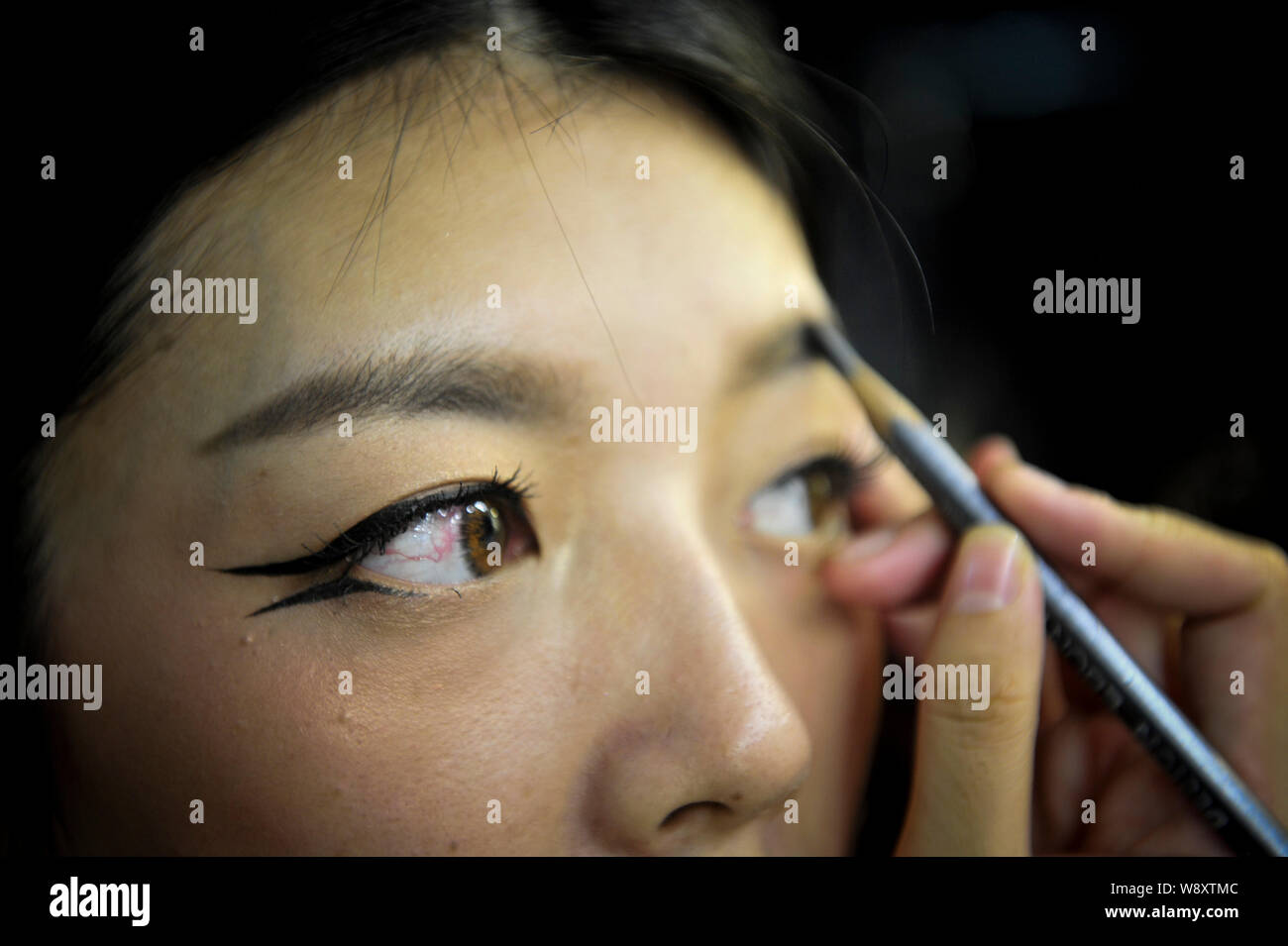 Chinese model Xiao Ya makes herself up during a photography session for ...