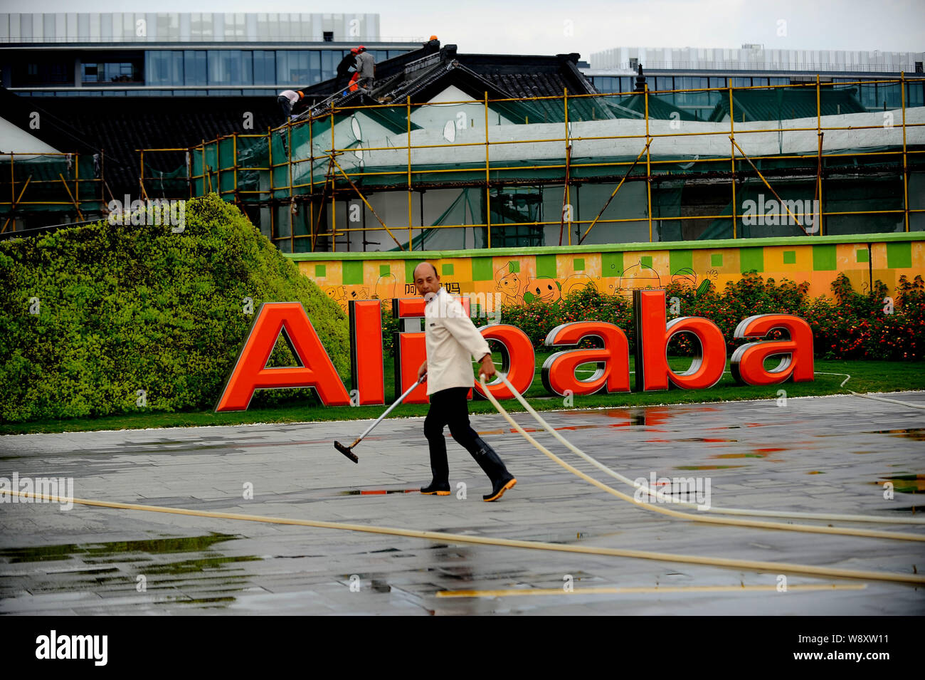 --FILE--A cleaning worker walks past a signboard of Alibaba at the ...
