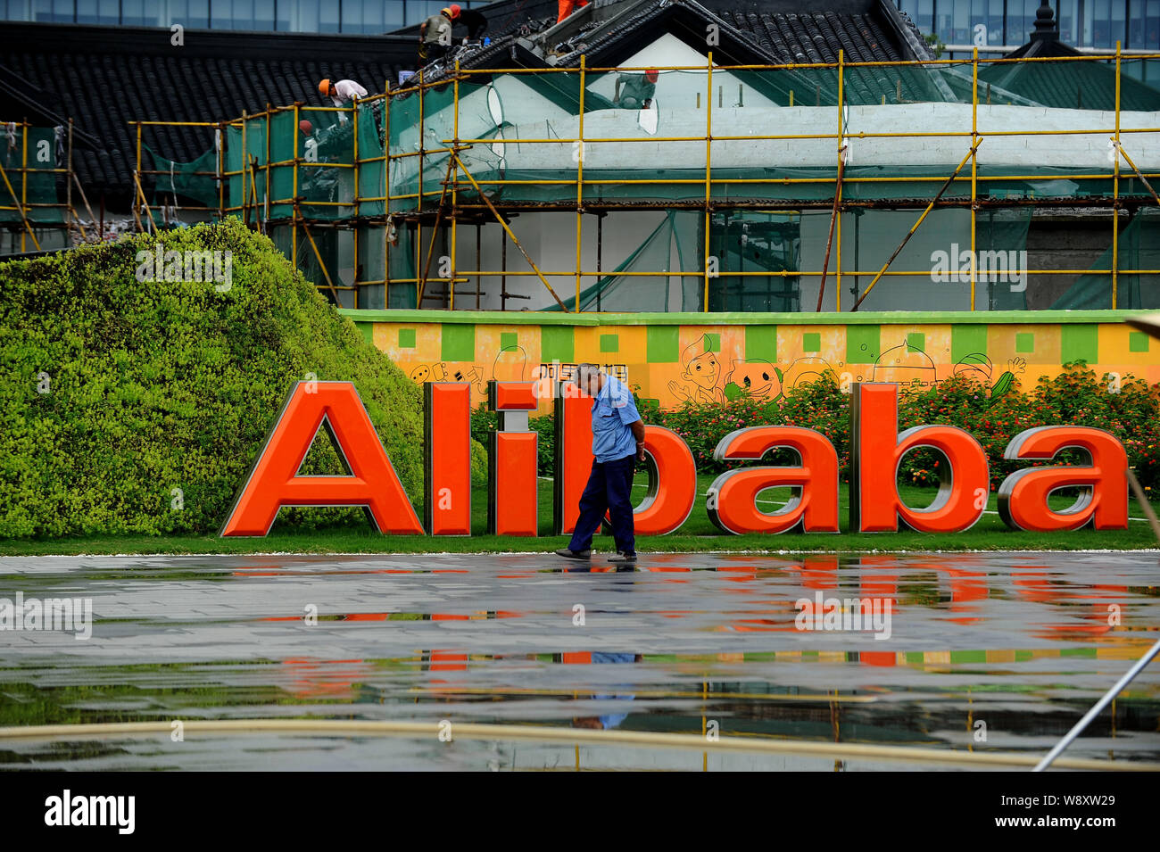 A Chinese worker walks past a logo of Alibaba at the headquarters of ...