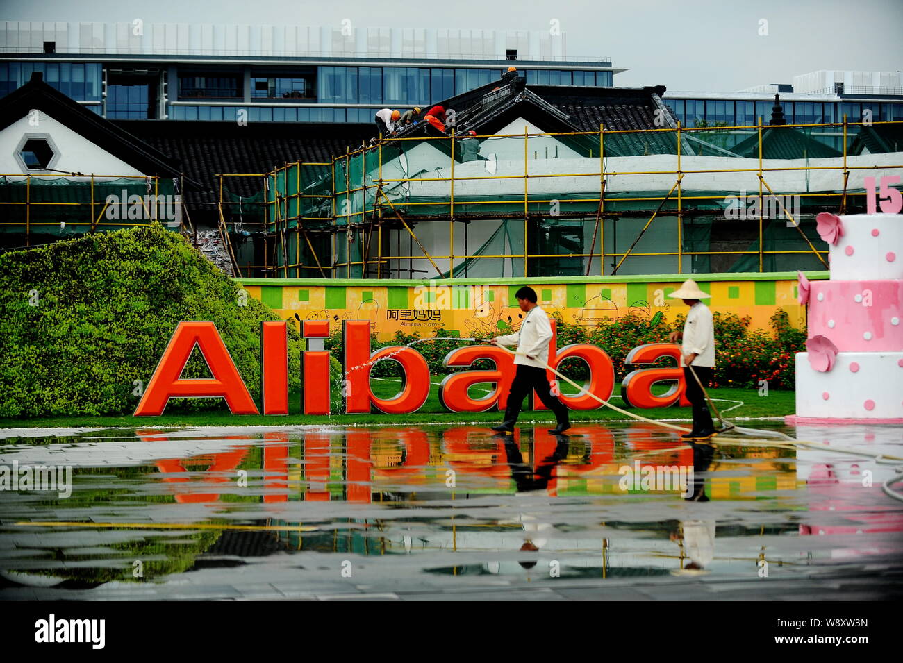--FILE--Cleaning workers wash the ground in front of a logo of Alibaba ...