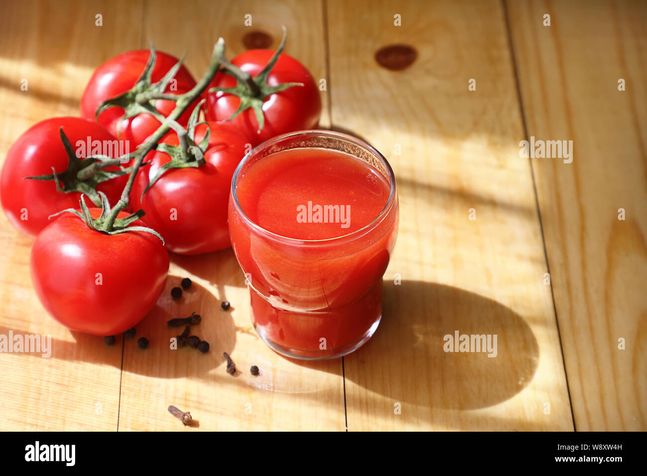 Tomato juice in a glass Cup with a bunch of ripe tomatoes, on a light ...