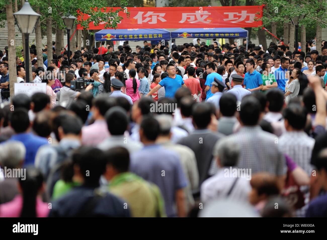 A crowd of Chinese parents, front, wait at the gate of a school for ...