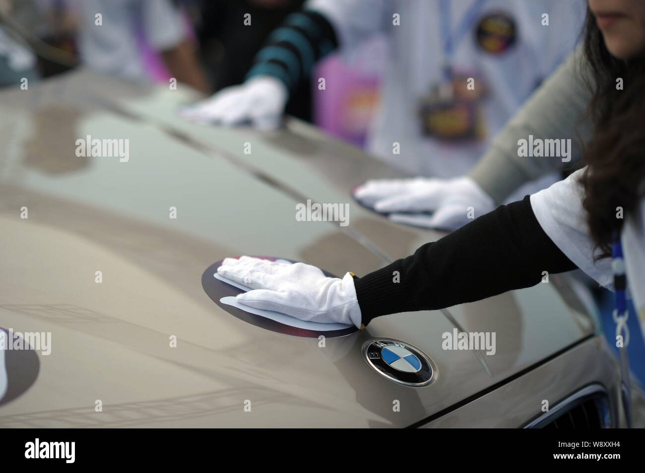 Chinese contestants keep their hands on a BMW X1 SUV while standing on ...