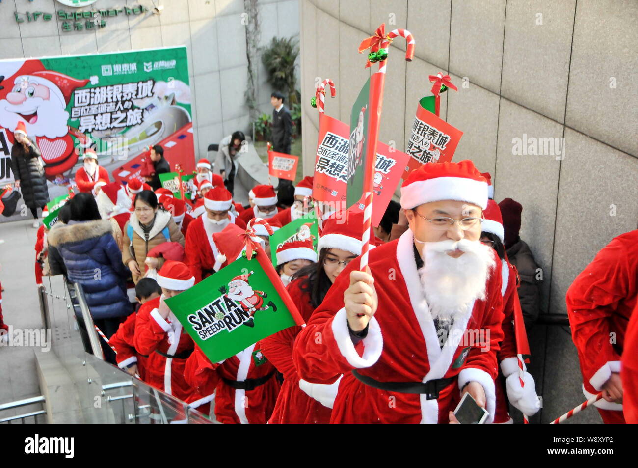 Chinese runners dressed in Santa Claus costumes wave flags during the ...