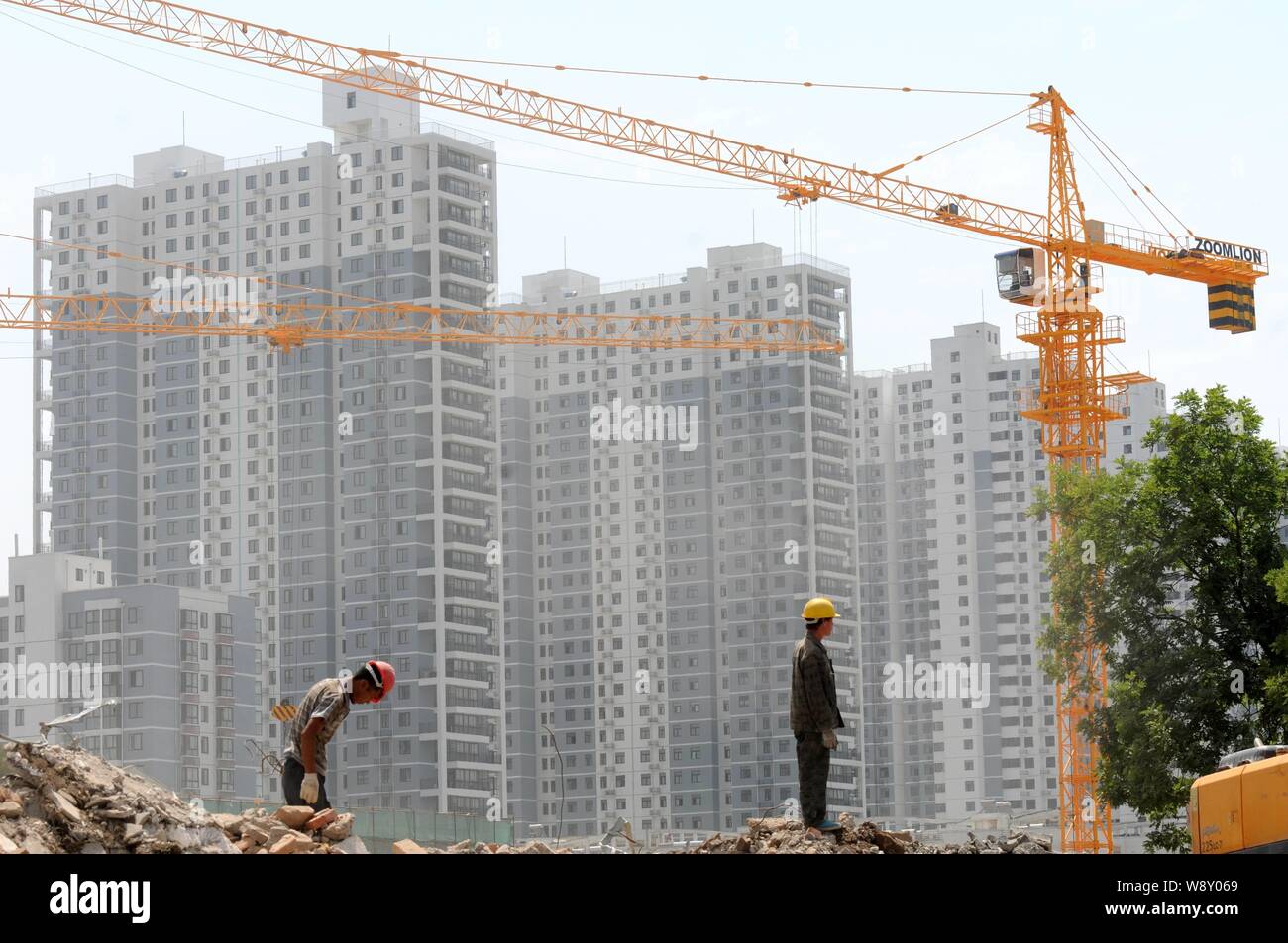 Chinese migrant workers labor at a construction site next to newly ...
