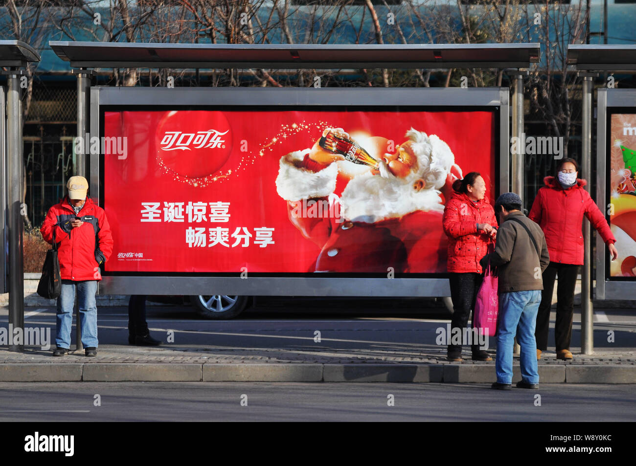 --FILE--Passengers wait in front of an advertisement for Coca-Cola at a ...