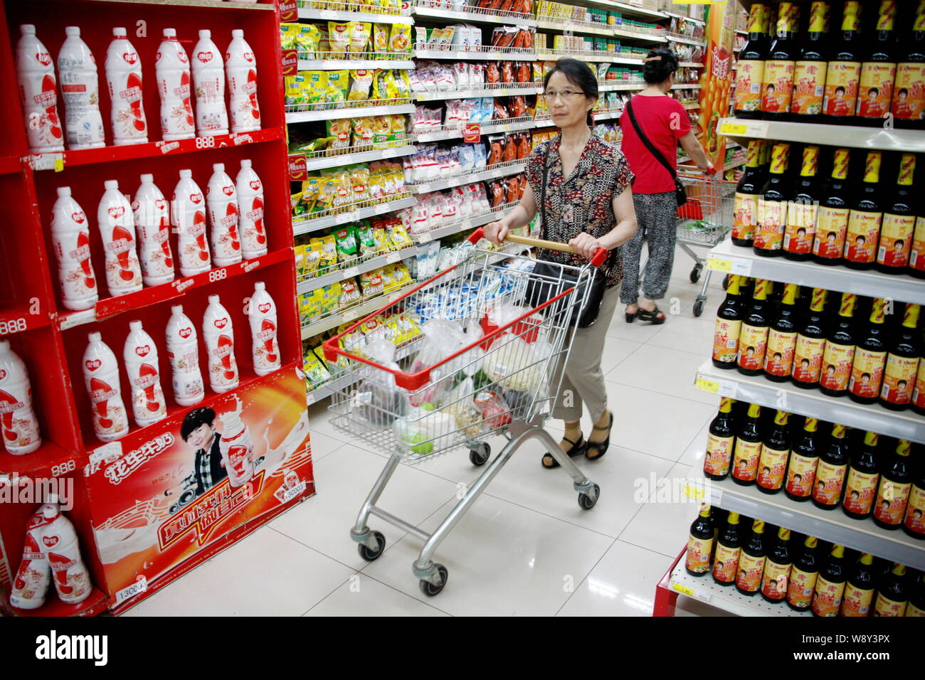 Chinese customers push shopping carts past flavors at a supermarket in ...