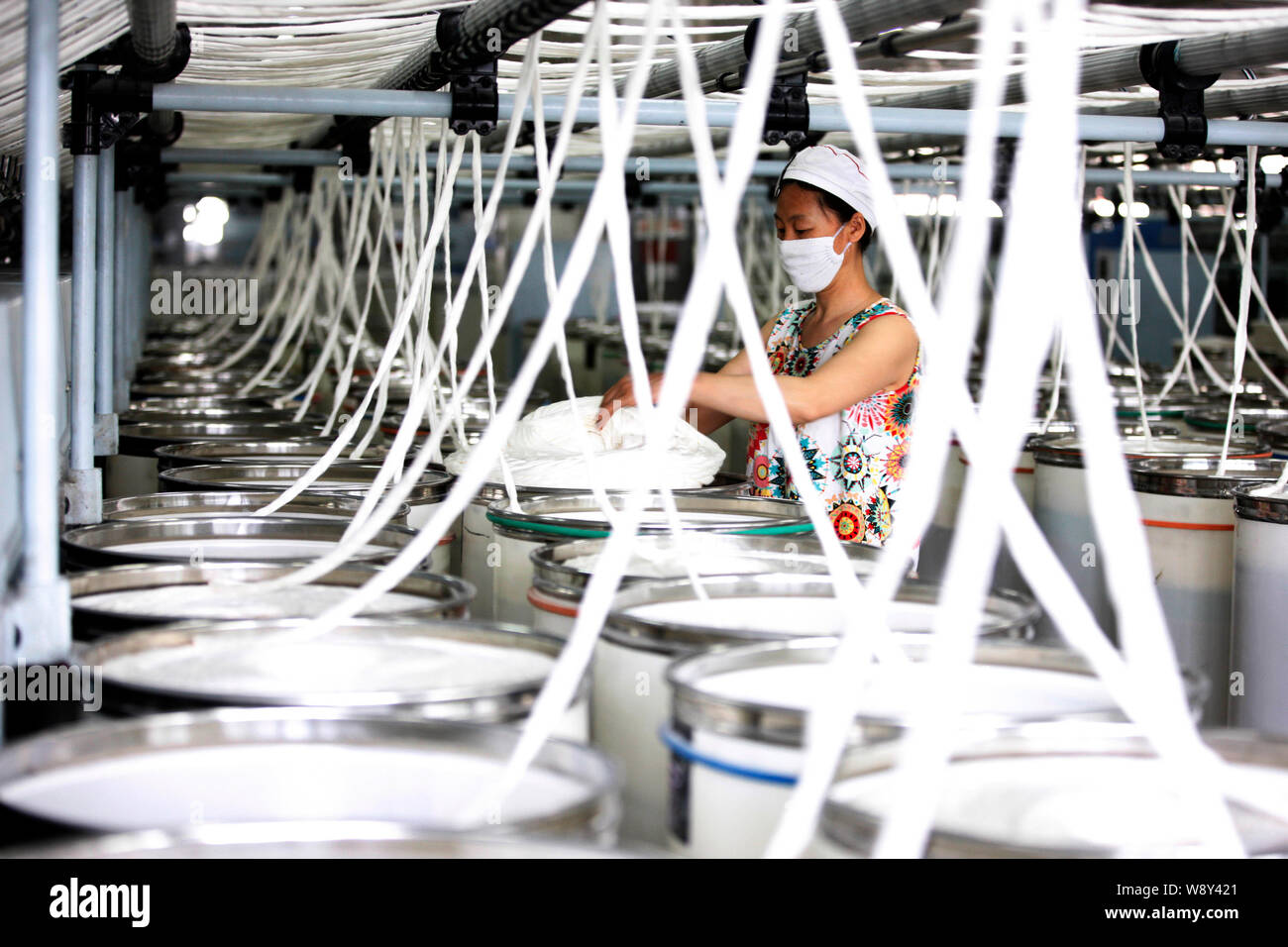 A female Chinese worker handles production of yarn to be exported to South Korea at a textile ...