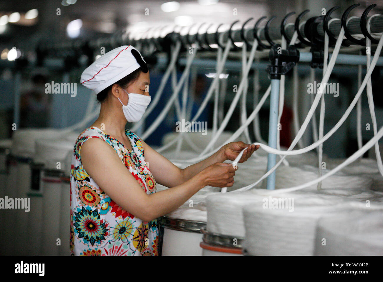 A female Chinese worker handles production of yarn to be exported to South Korea at a textile ...