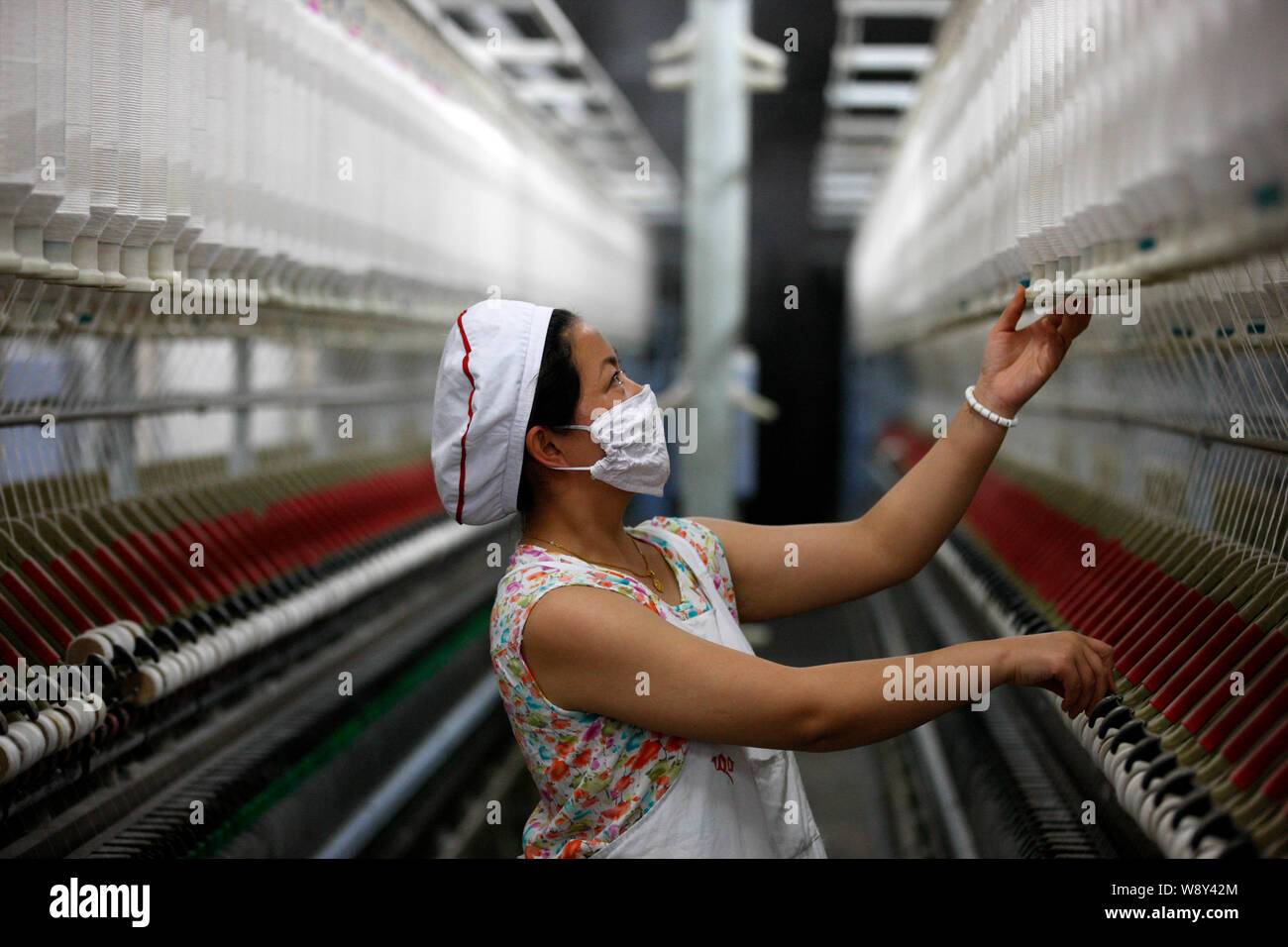 A female Chinese worker handles production of yarn to be exported to South Korea at a textile ...