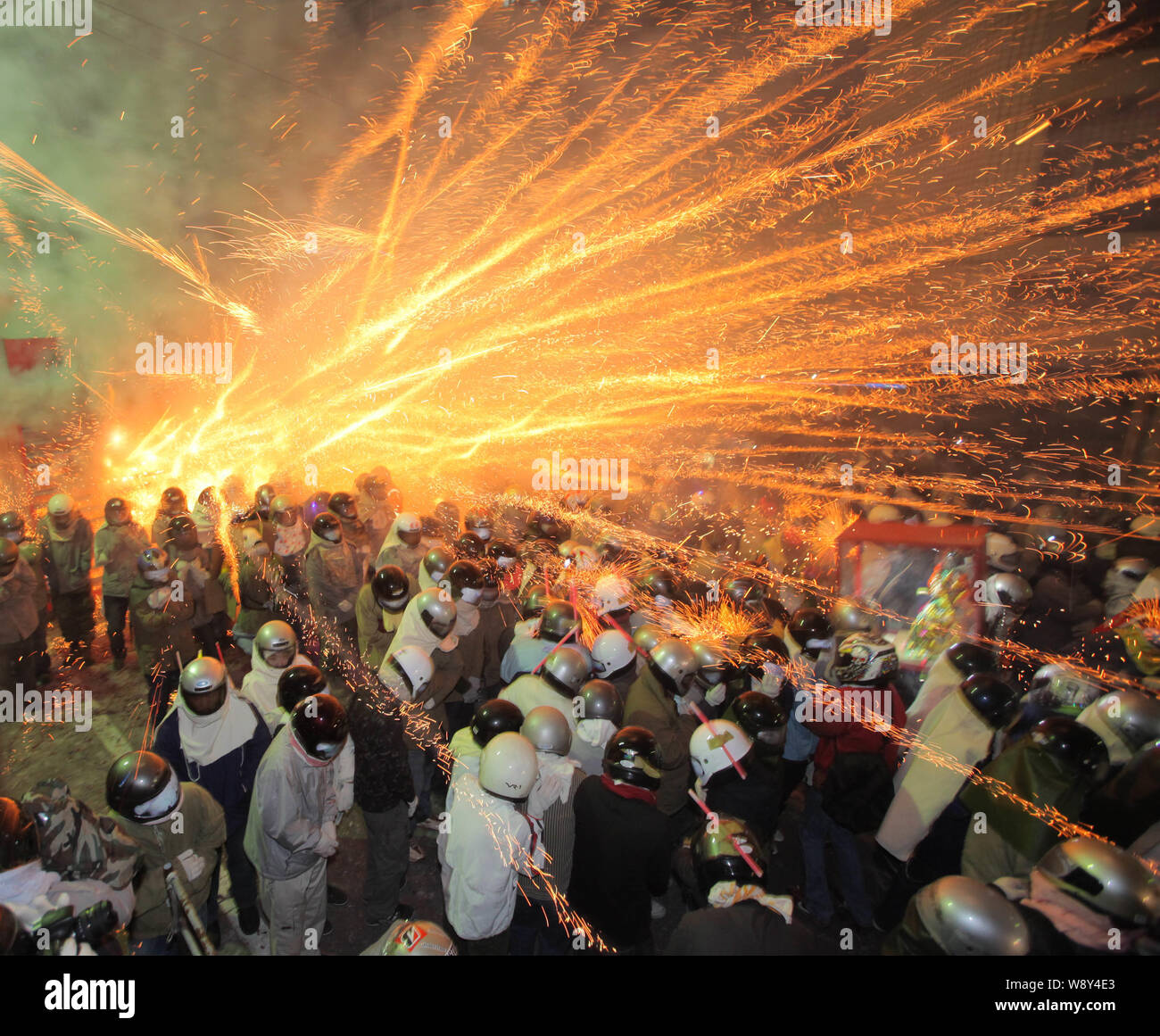--FILE--Visitors wearing helmets get sprayed by fire sparks from ...