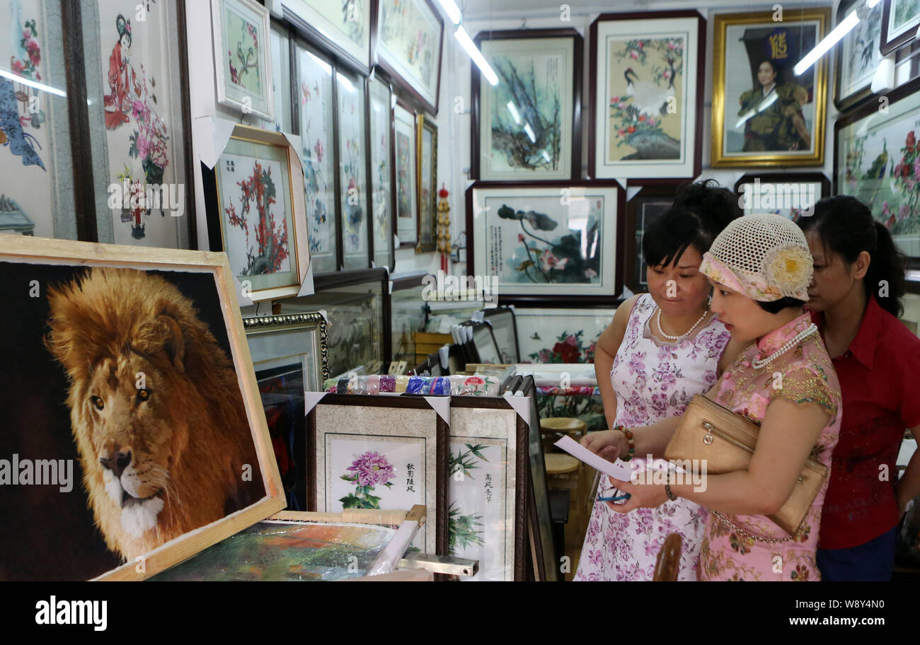35-year-old Yang Xiaoting, front, talks with a crafts store owner as ...