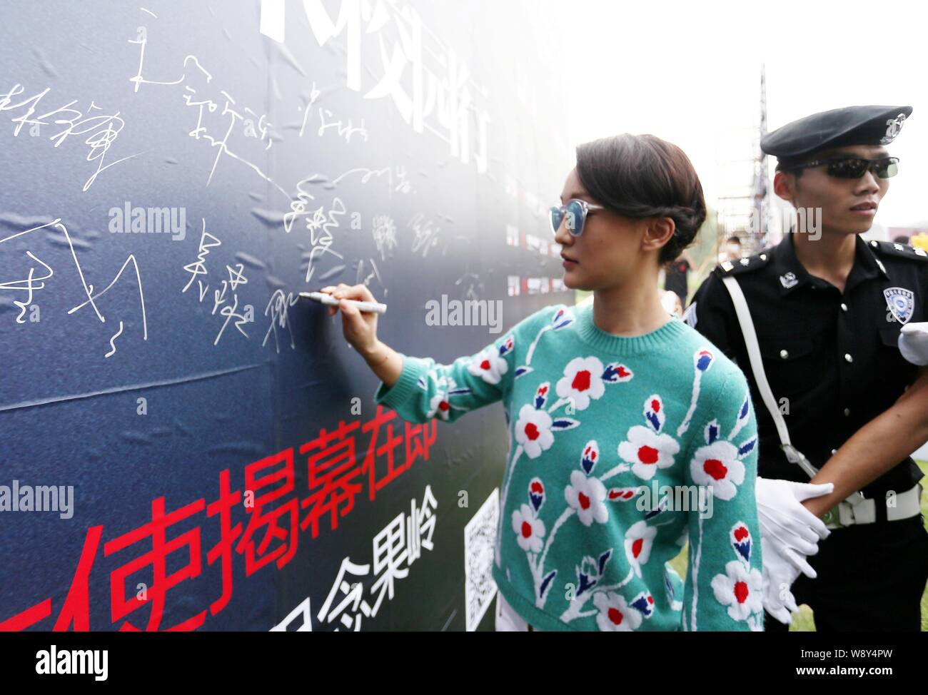 Chinese actress Zhou Xun, left, signs her autograph on a board at a ...