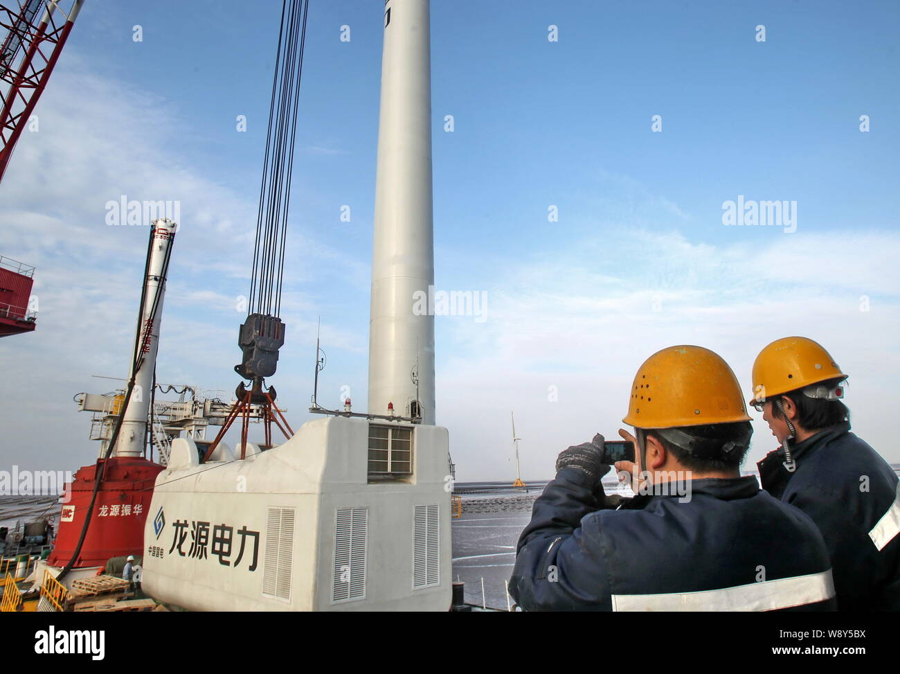 --FILE--Chinese workers look at a wind turbine of China Longyuan Power ...