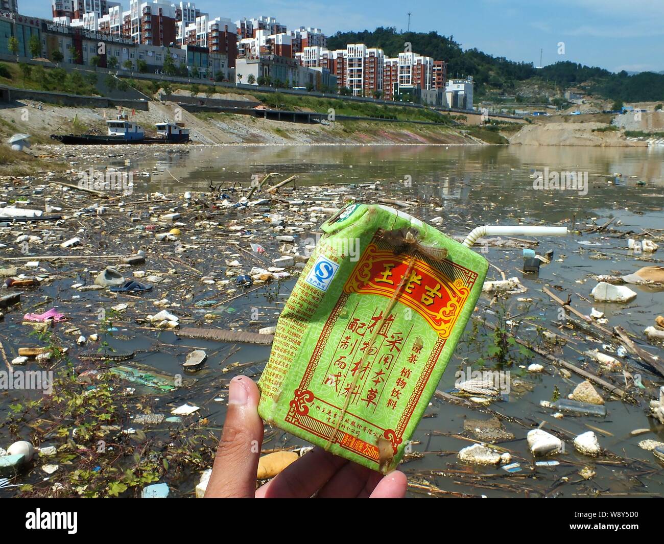 A Chinese worker shows a beverage carton collected from the floating ...
