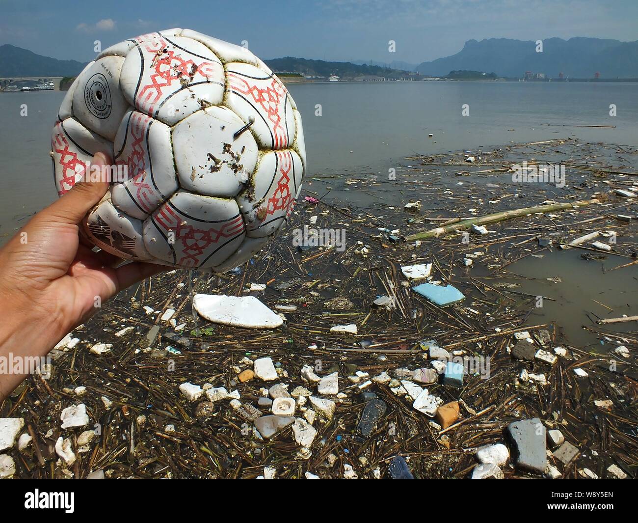 A Chinese worker shows a football collected from the floating garbage ...