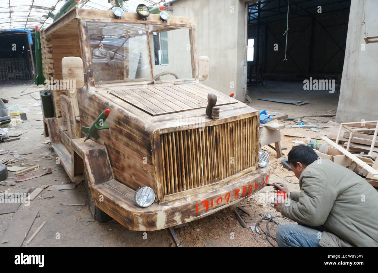Chinese carpenter Liu Fulong paints the bumper of his homemade electric ...