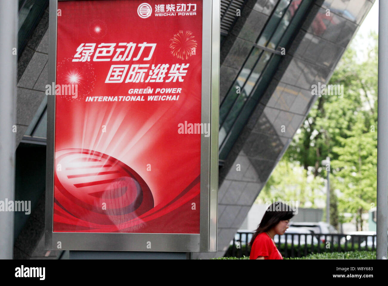 --FILE--A pedestrian walks past an advertisement for Weichai Power in ...