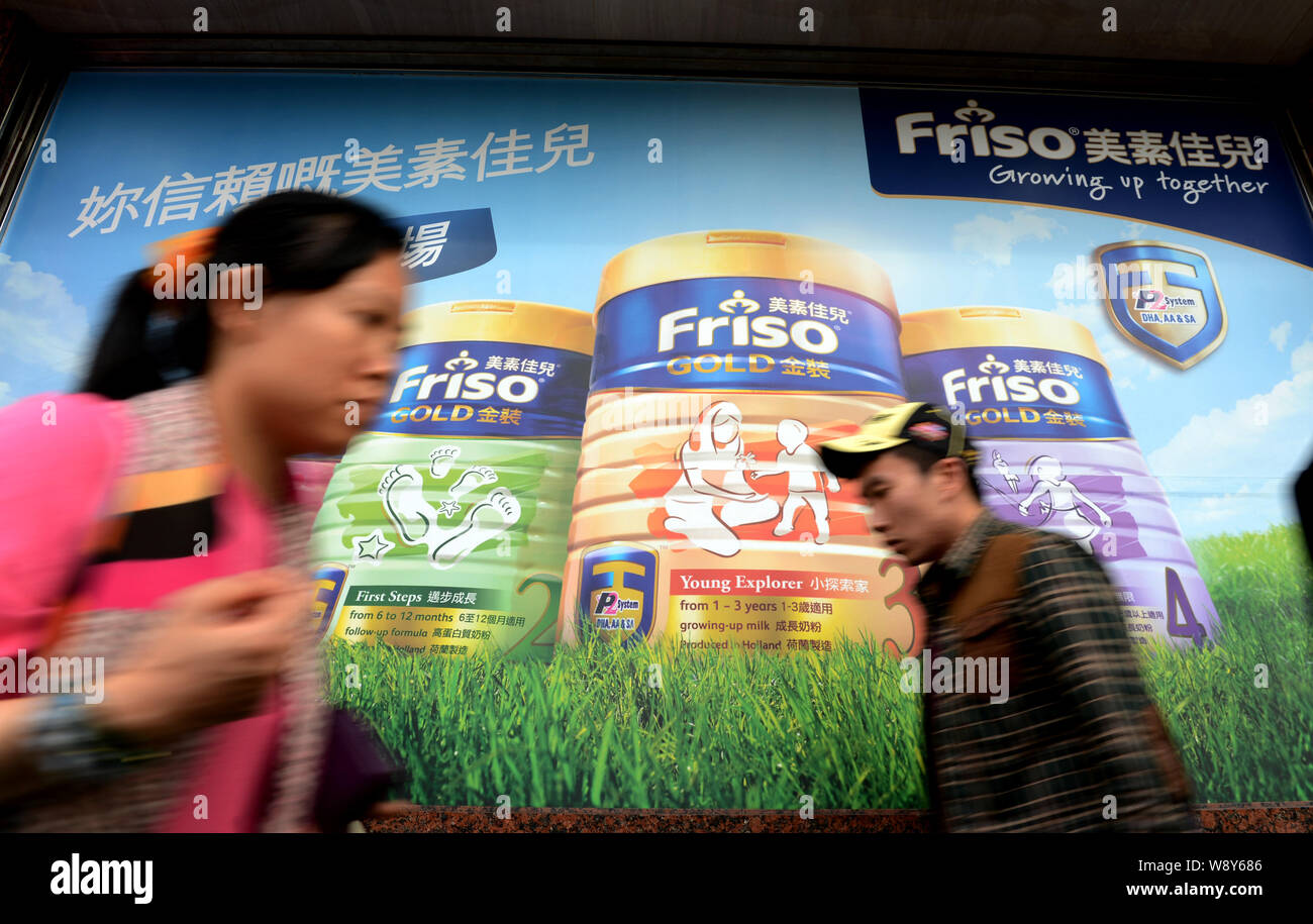 --FILE--Pedestrians walk past an advertisement for Friso baby milk ...