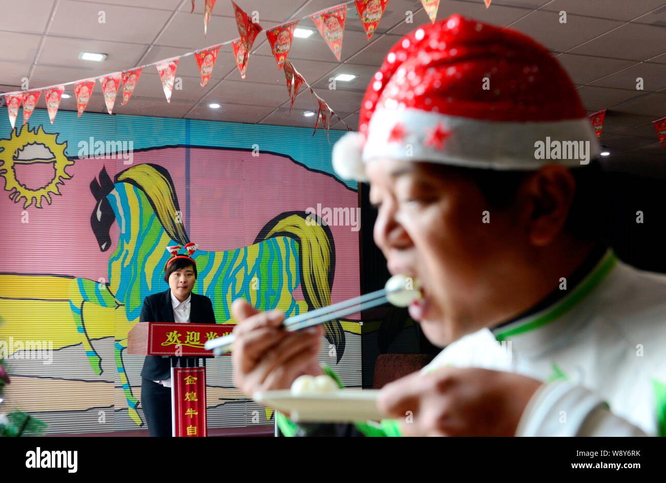 A Chinese waitress, back, watches big eater Pan Yizhong eating eggs ...