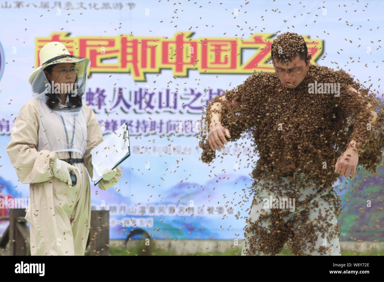 An officer of the World Record Association times Chinese beekeeper Ruan ...