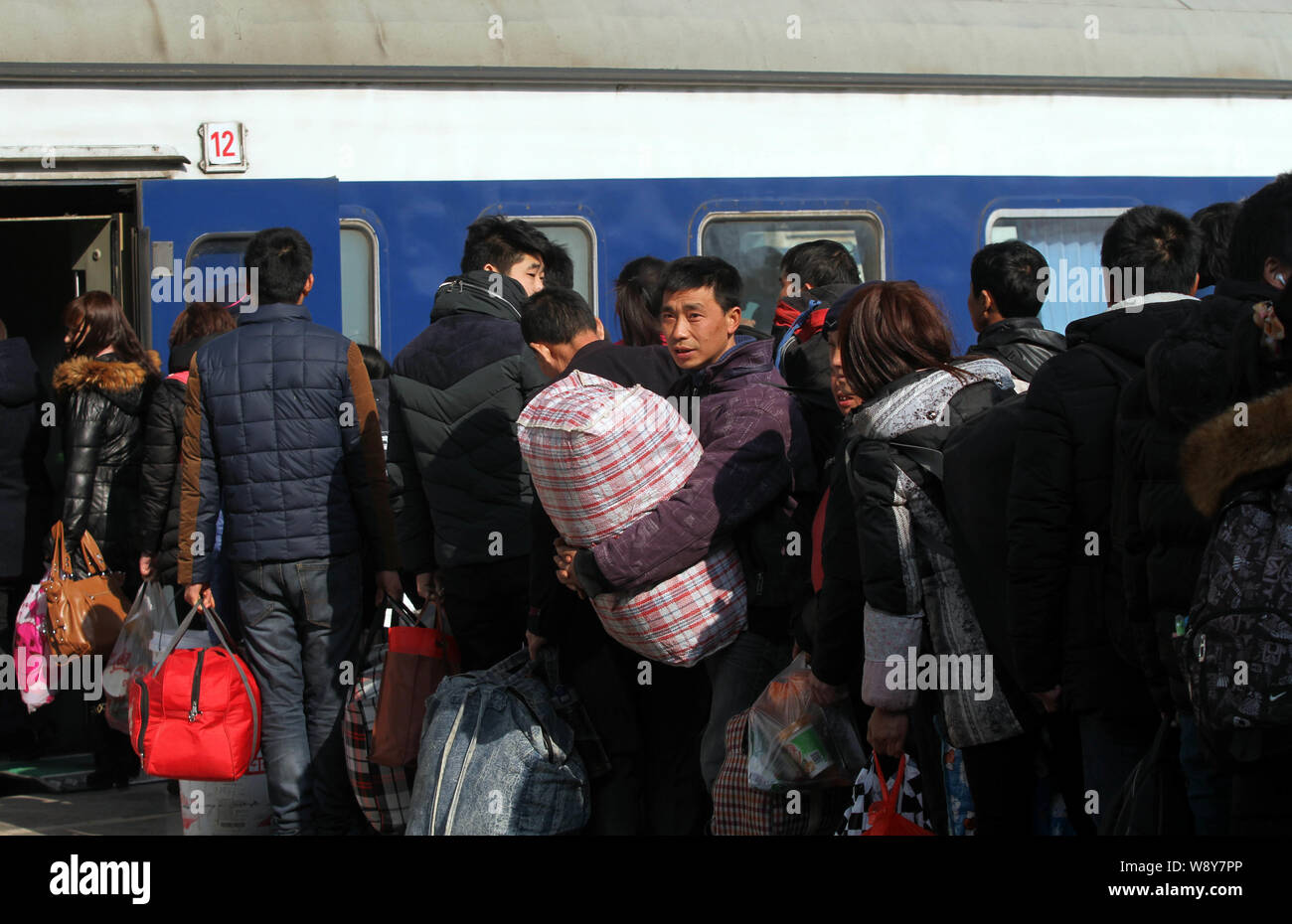 Migrant workers and other passengers queue up to board a train at the ...