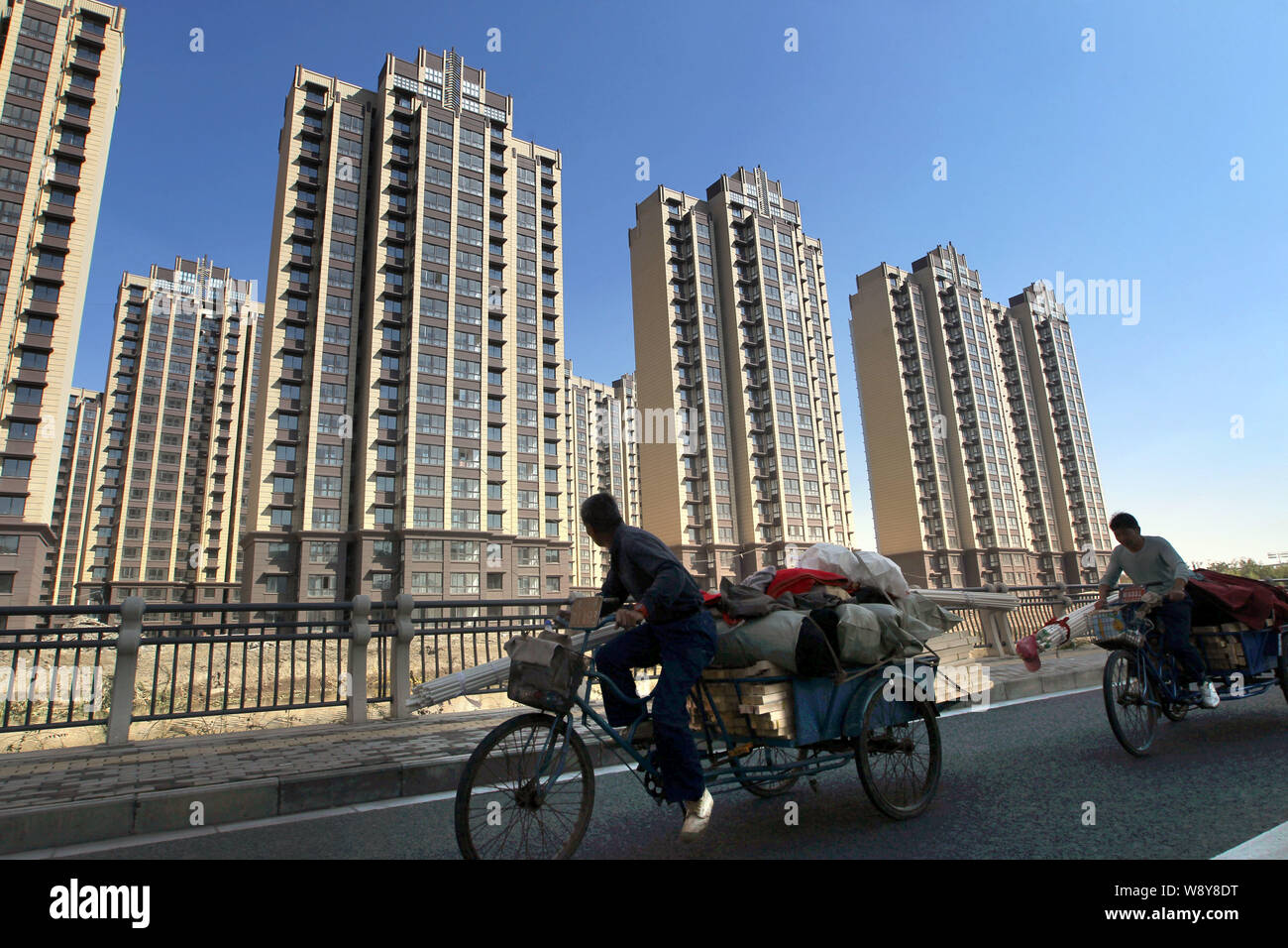 --FILE--Chinese workers ride tricycles past apartment buildings of a ...