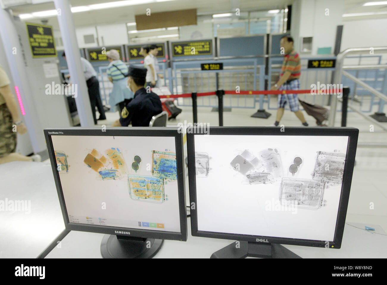 A Chinese customs officer uses a scanner to check the belongings of a ...