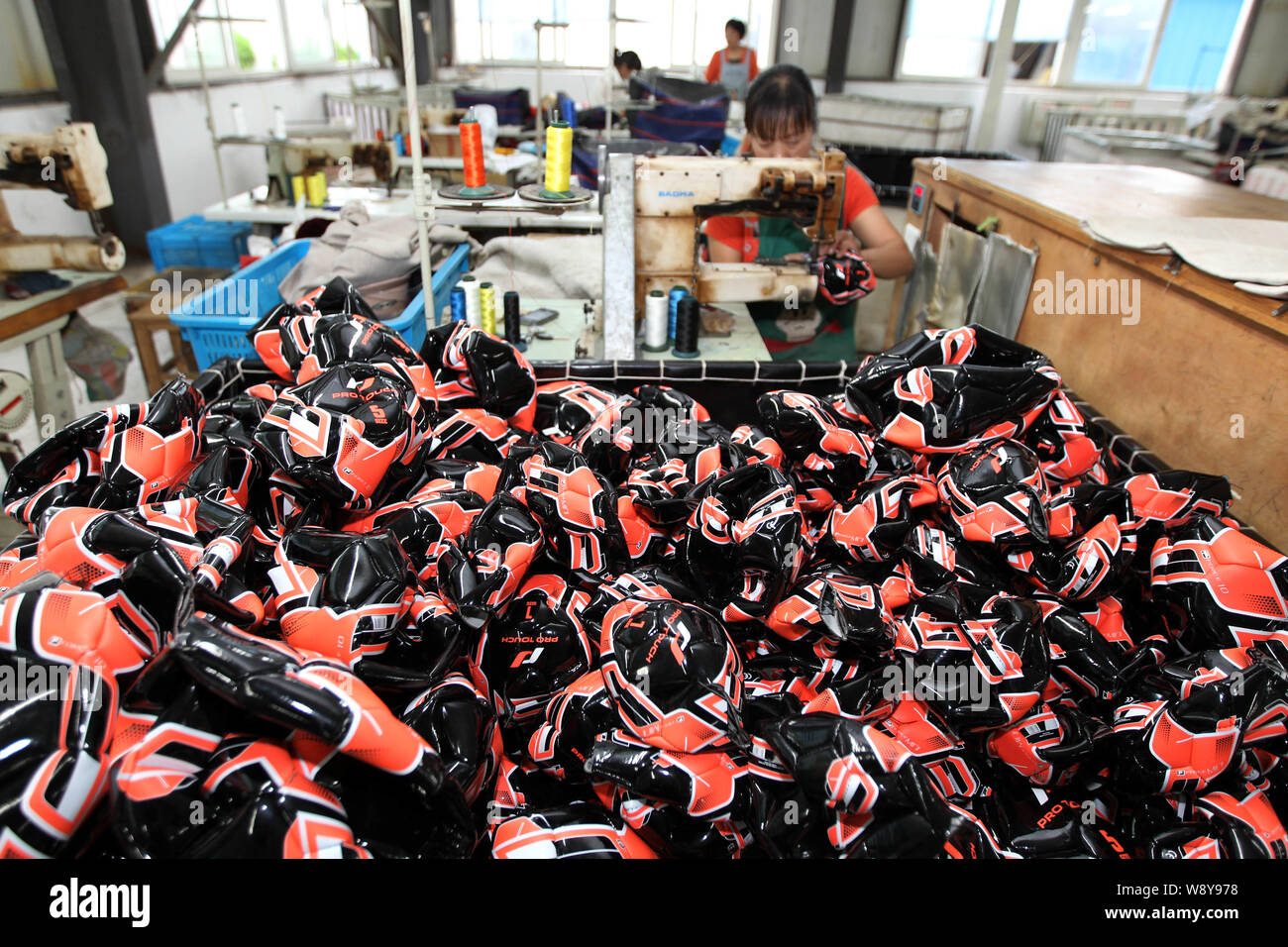 A Chinese worker sews panels to make a football at a sports goods ...