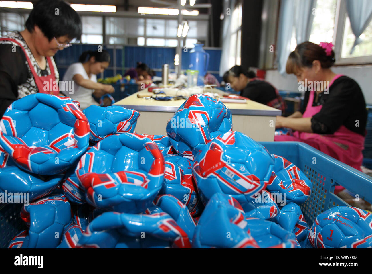 Chinese workers sew panels to make footballs at a sports goods factory ...