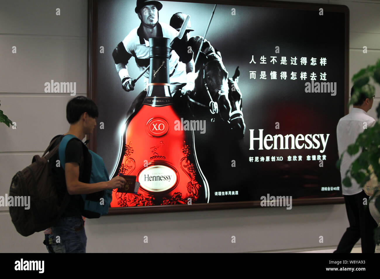--FILE--Pedestrians walk past an advertisement for Hennessy XO cognac ... --FILE--Pedestrians walk past an advertisement for Hennessy XO cognac ...