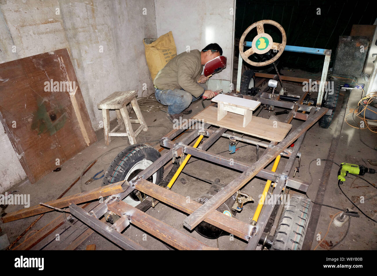 Chinese carpenter Liu Fulong welds the chassis of his homemade electric ...
