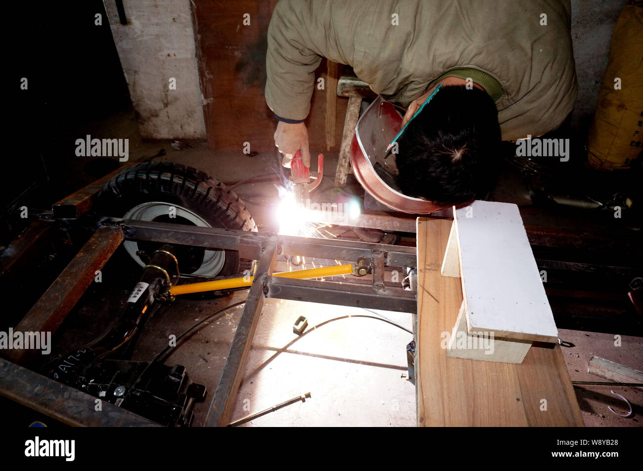 Chinese carpenter Liu Fulong welds the chassis of his homemade electric ...